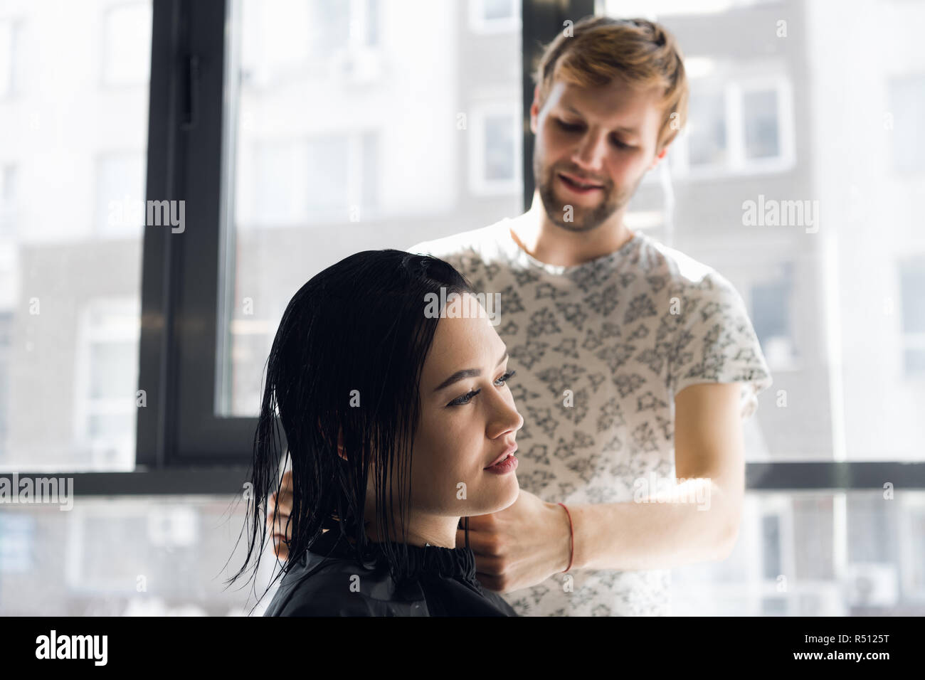 Smiling woman getting haircut by handsome hairdresser Stock Photo - Alamy