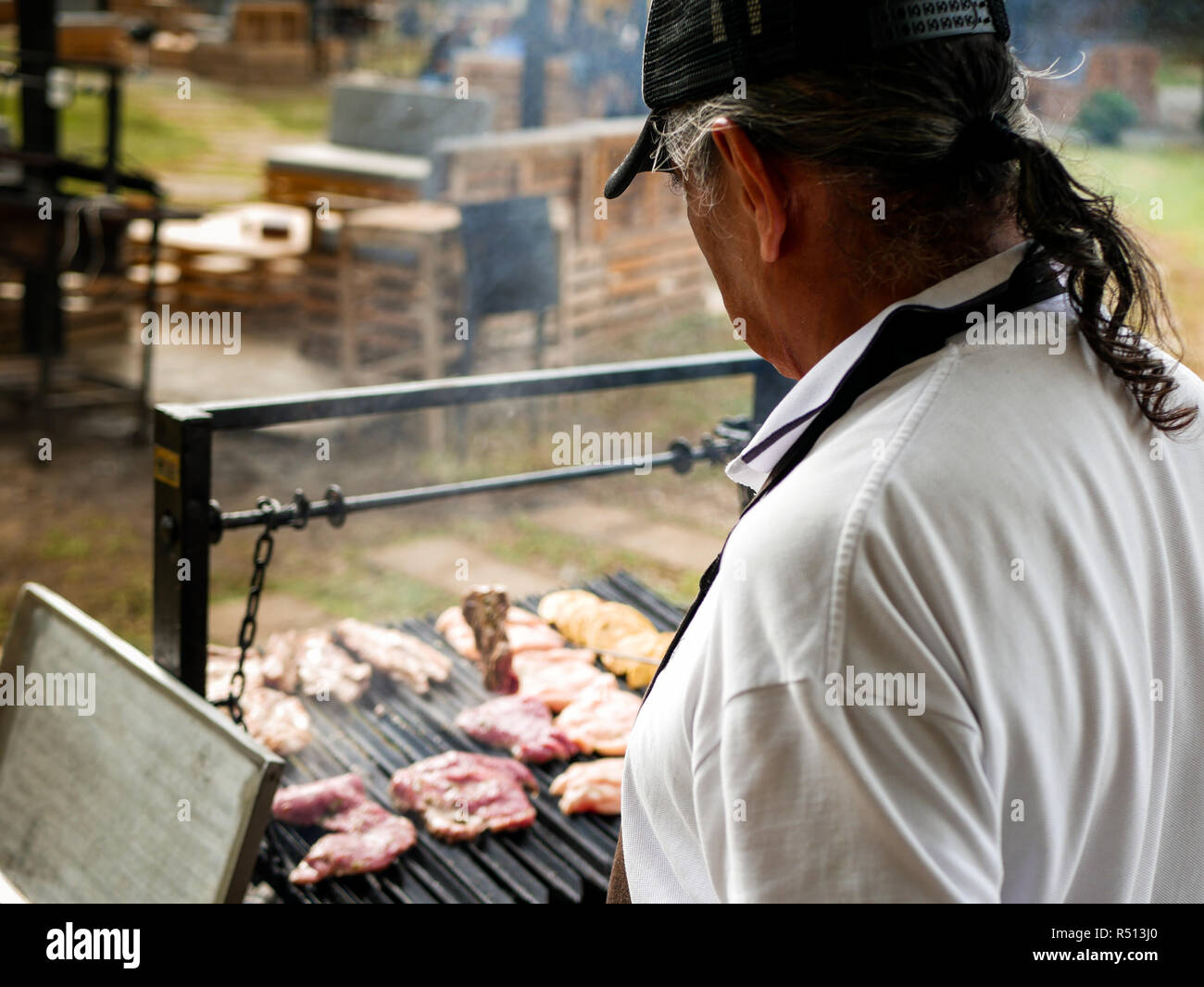 back of an old man with a pony tail making a barbecue for a party the ...