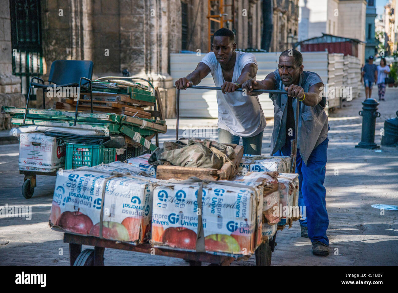 Labors pushing boxes on a platform trolley in the streets of Havana ...