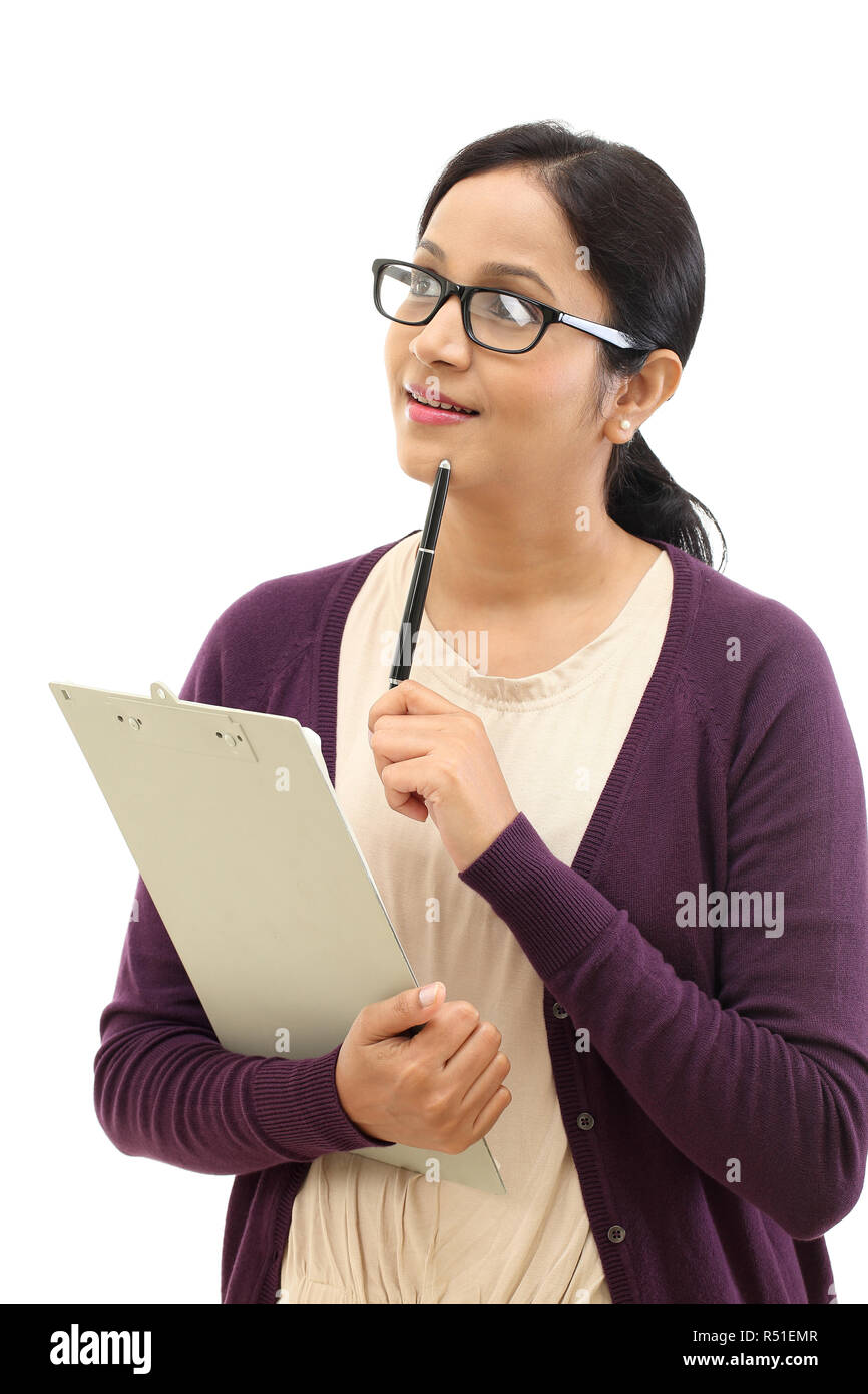 Young woman thinking while taking notes against white background Stock ...