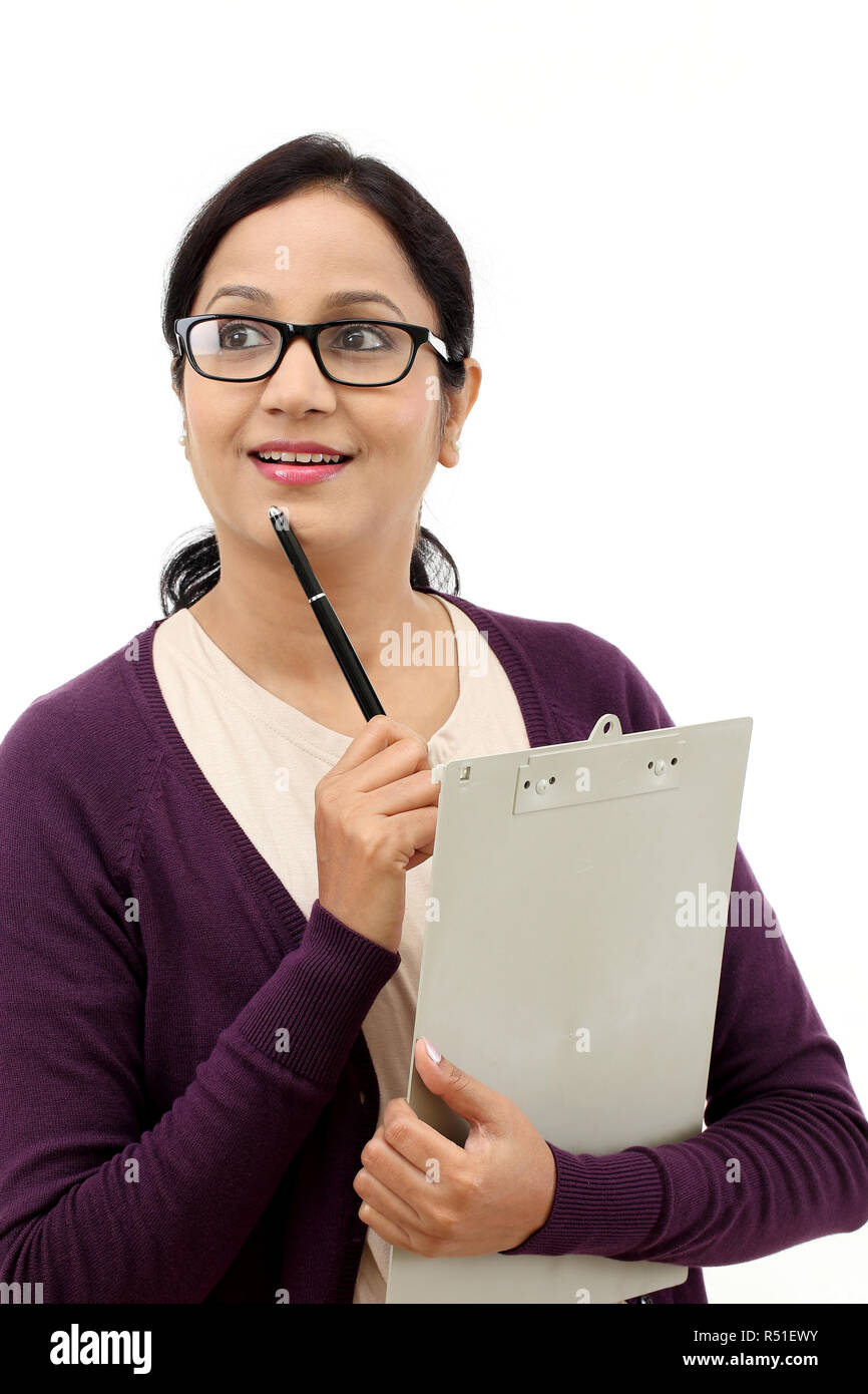 Young woman thinking while taking notes against white background Stock ...