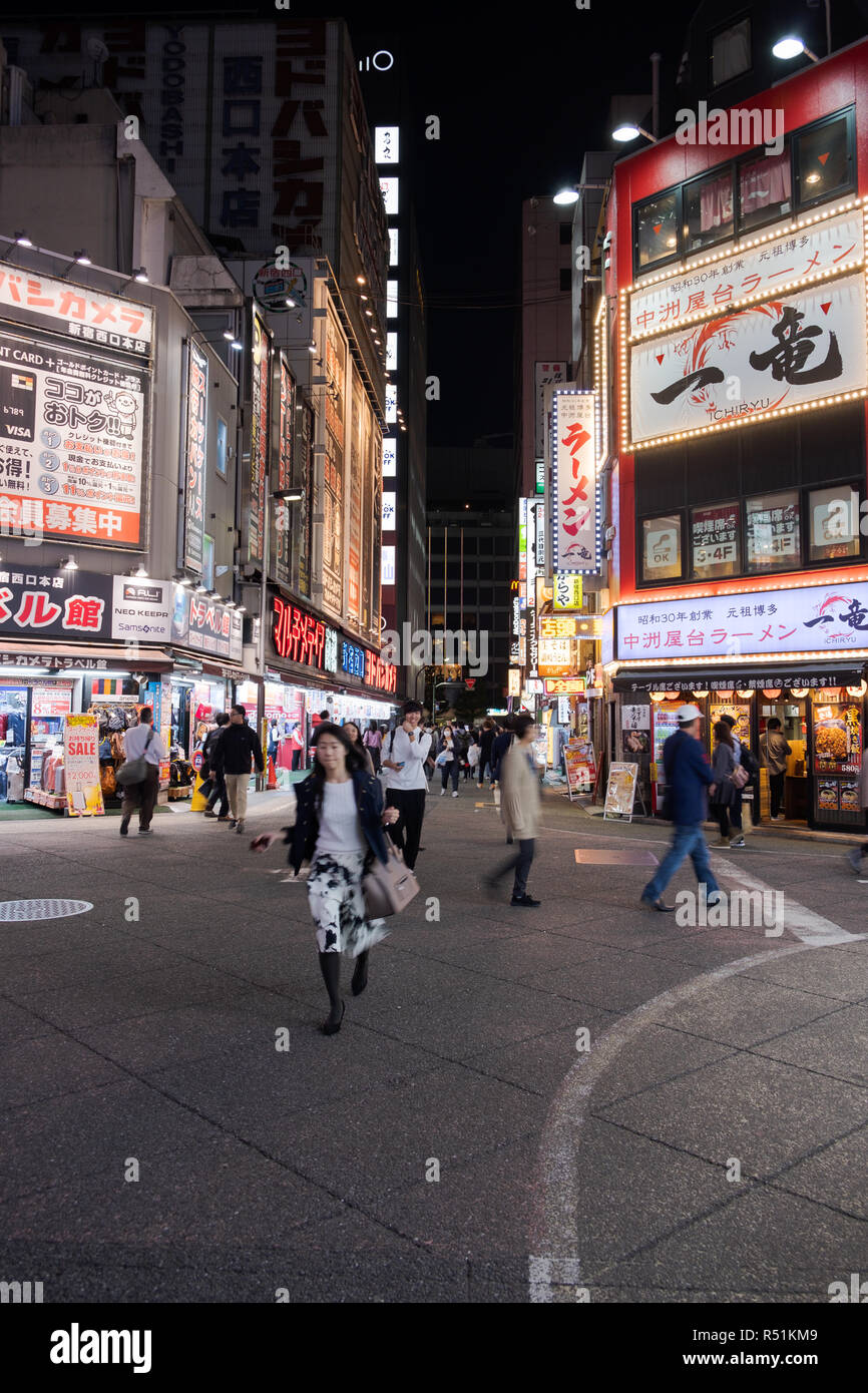 Main street in Shinjuku, Tokyo, Japan at night with pedestrians walking ...