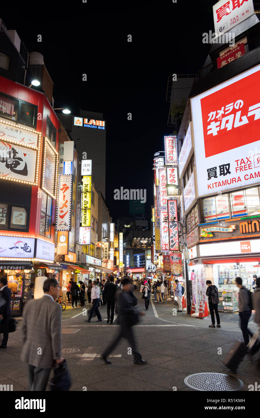 Main street in Shinjuku, Tokyo, Japan at night with pedestrians walking ...