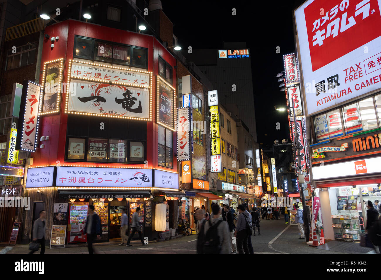Main street in Shinjuku, Tokyo, Japan at night with pedestrians walking ...
