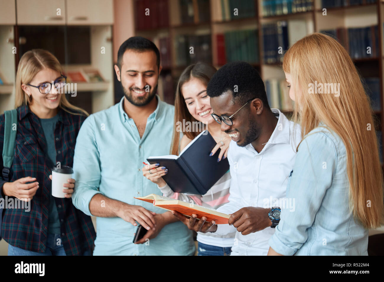 Portrait of young multicultural friends reading books together in the ...