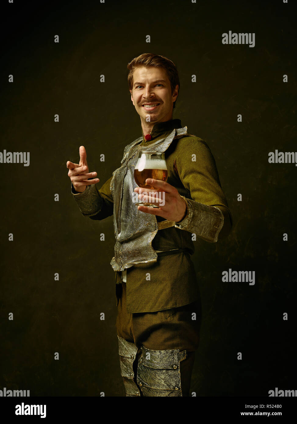 Medieval smiling happy knight with beer on dark studio background ...