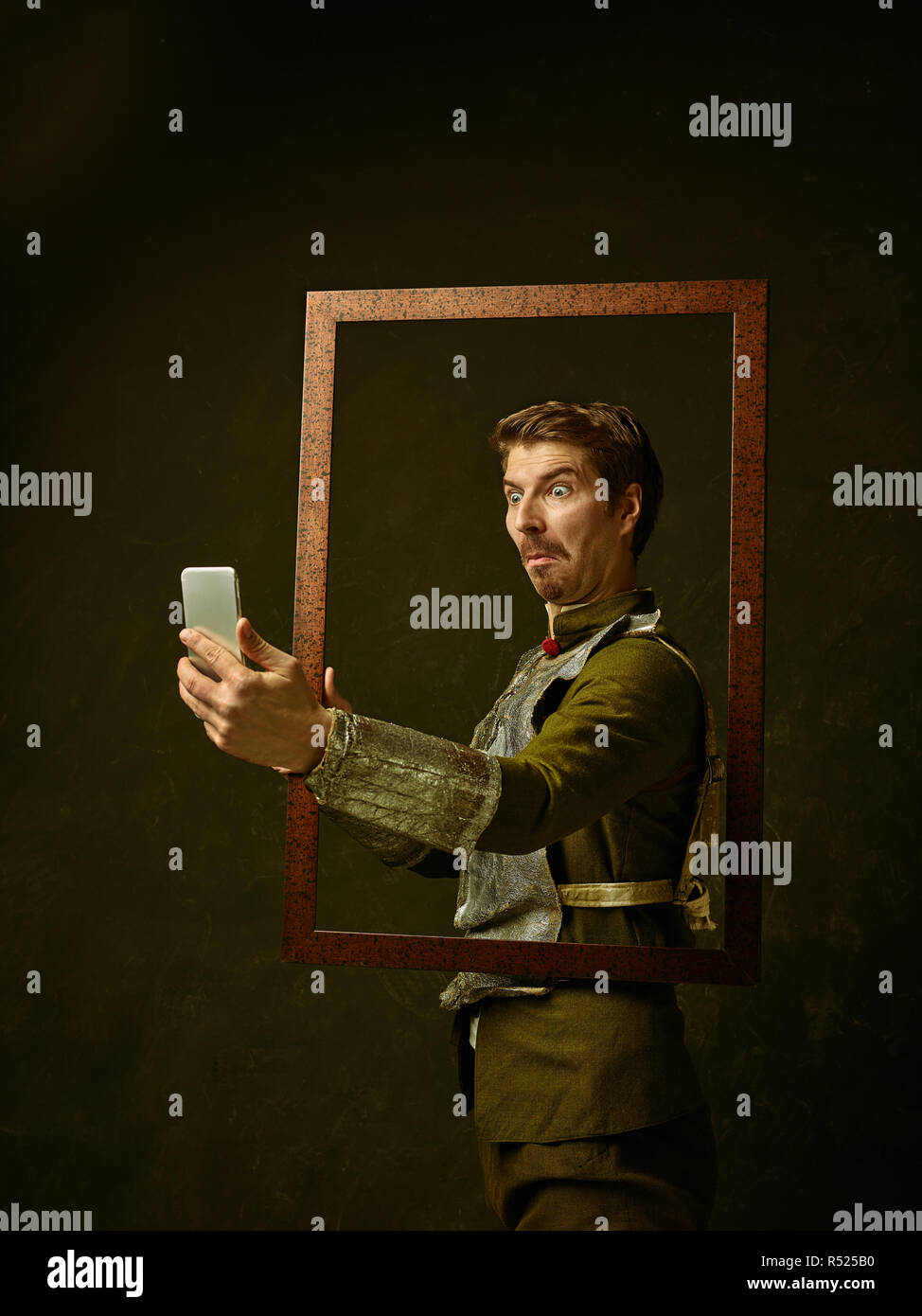 Medieval knight with mobile phone on dark studio background. Portrait ...