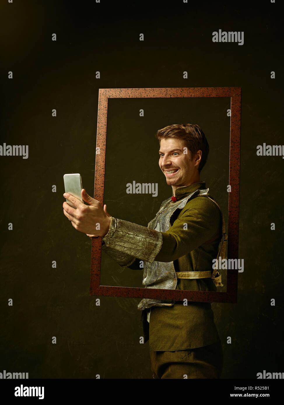 Medieval knight with mobile phone on dark studio background. Portrait ...