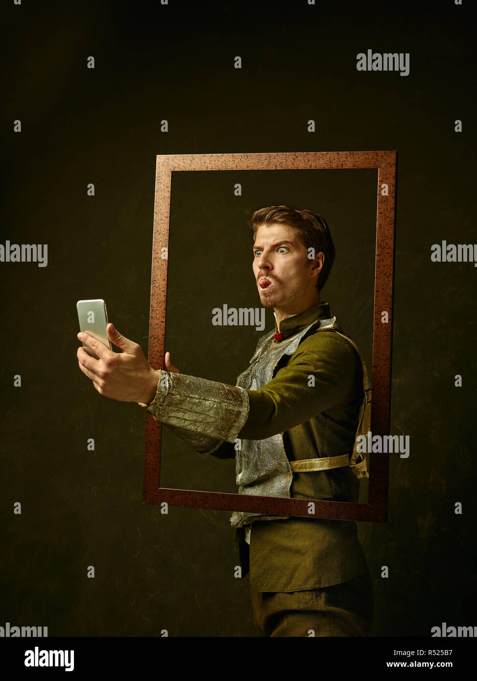 Medieval knight with mobile phone on dark studio background. Portrait ...