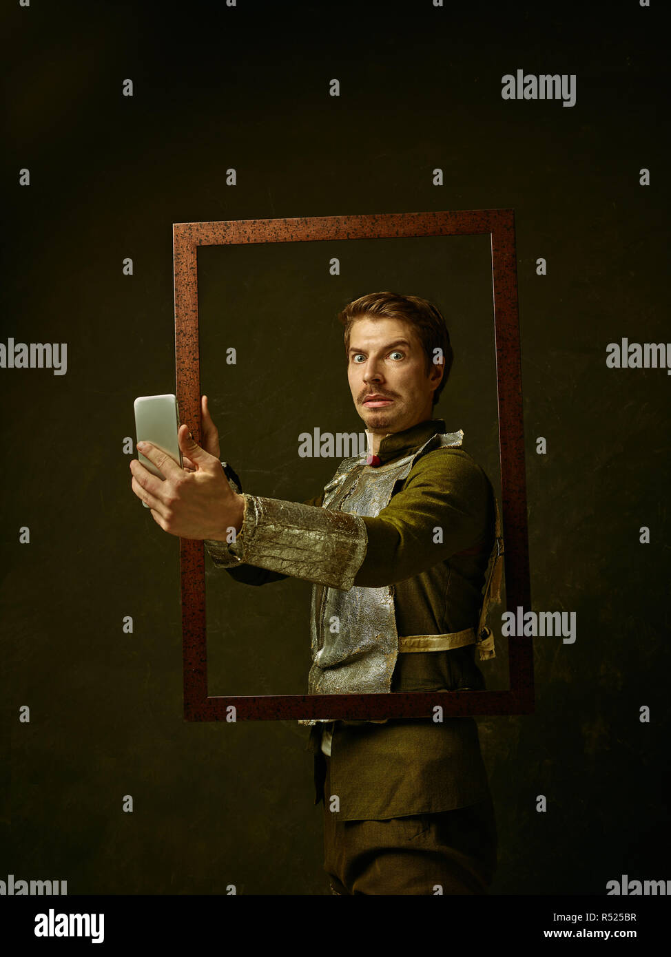 Medieval knight with mobile phone on dark studio background. Portrait ...