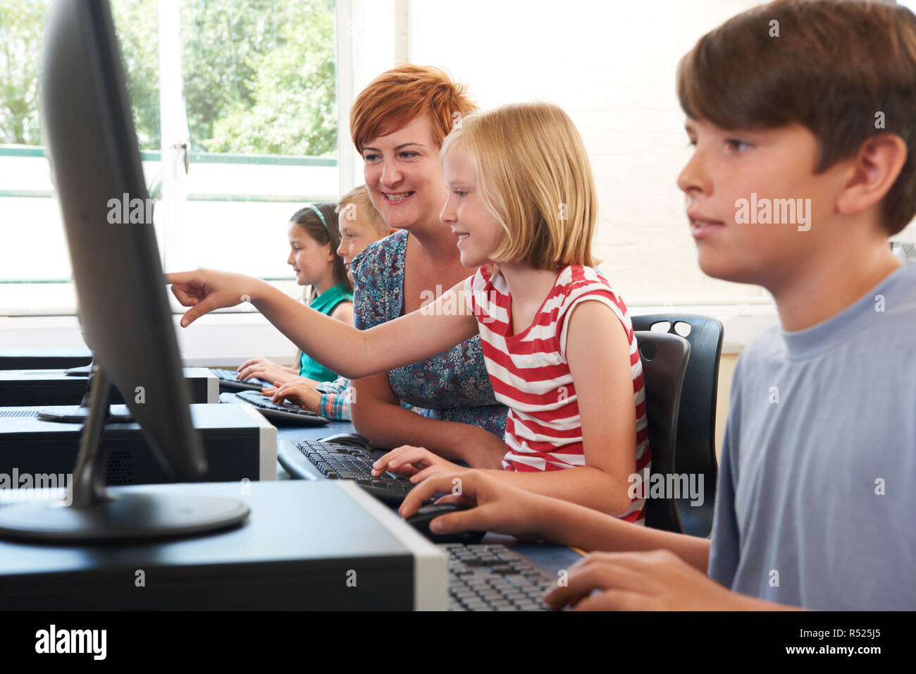 Female Elementary Pupil In Computer Class With Teacher Stock Photo - Alamy