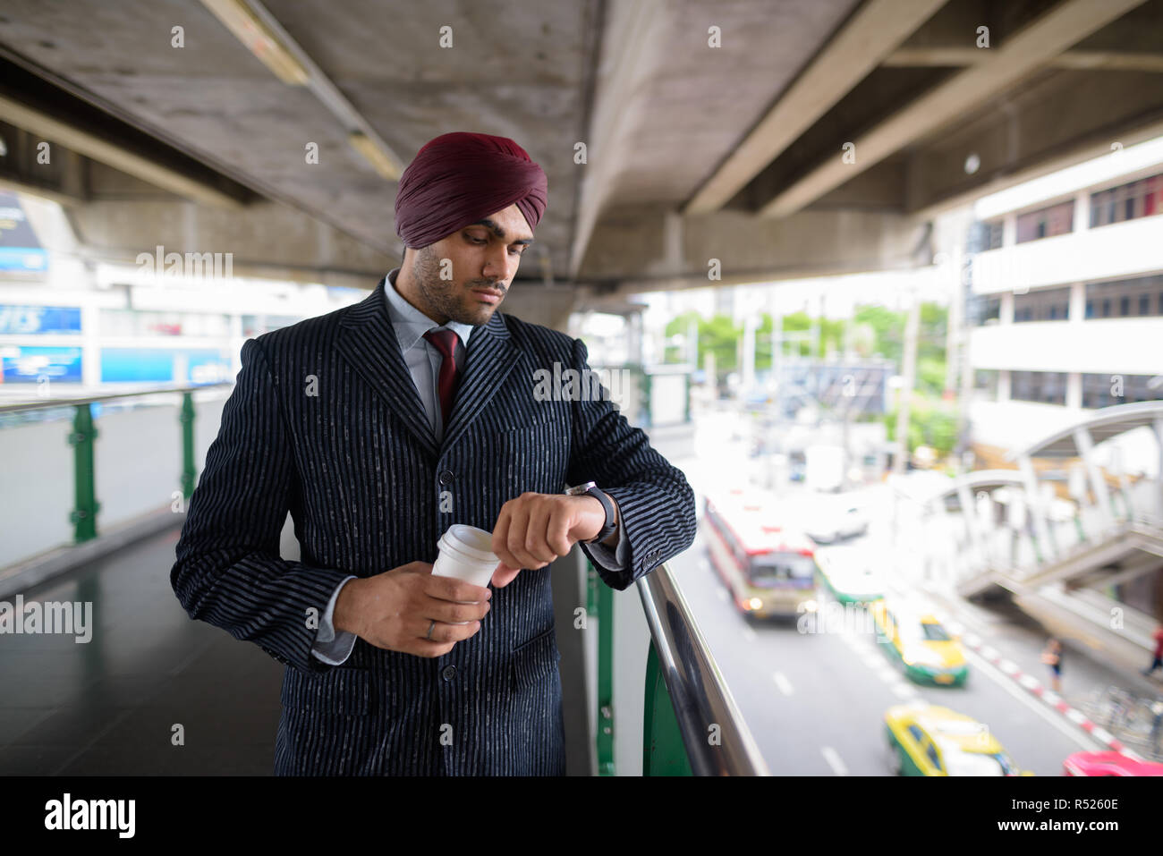 Indian Sikh businessman checking smart watch and holding coffee Stock ...