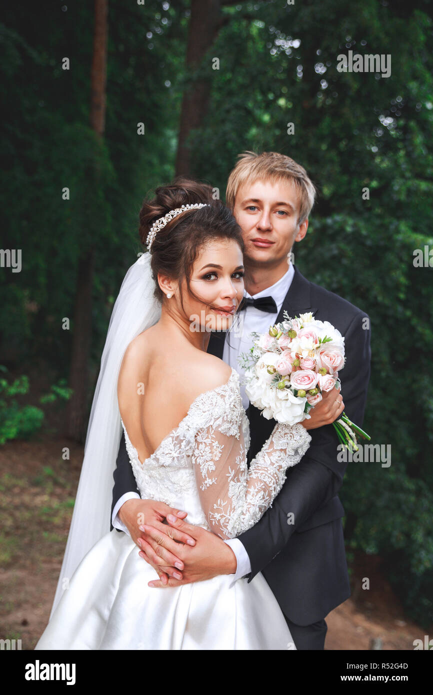 Beautiful wedding couple in park. Bride and groom hug each other ...