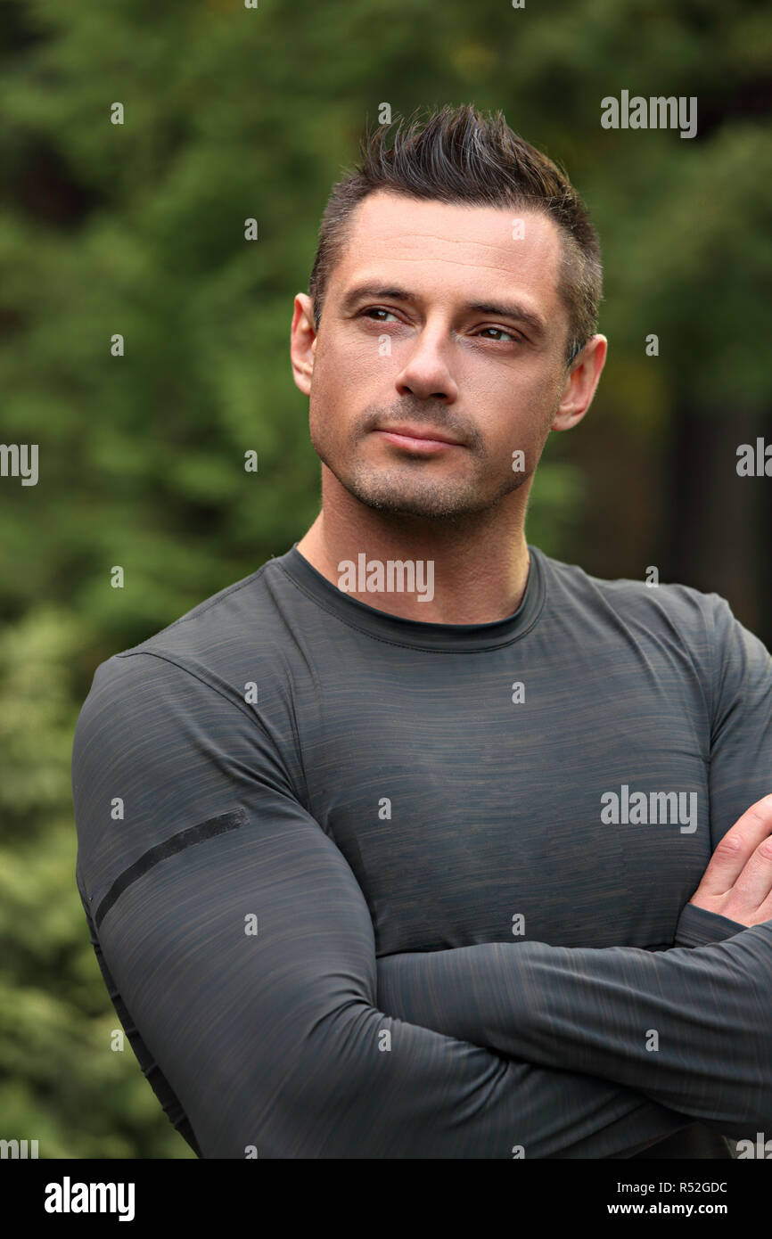 Strong handsome man thinking looking on summer green trees background ...