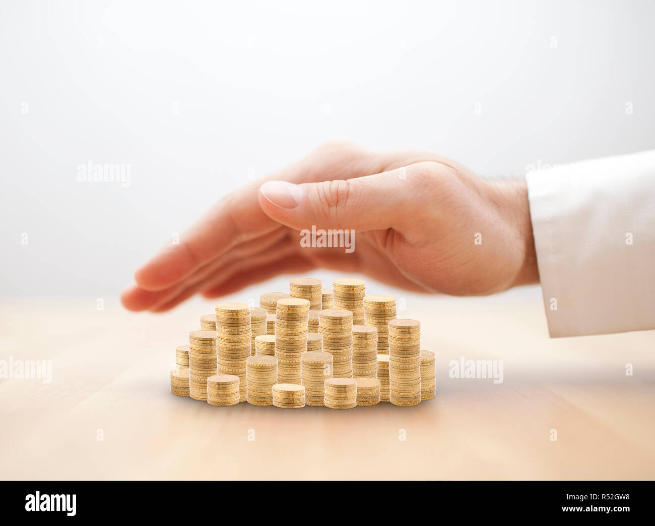 Stack of golden coins covered by hand. Savings protection concept Stock ...