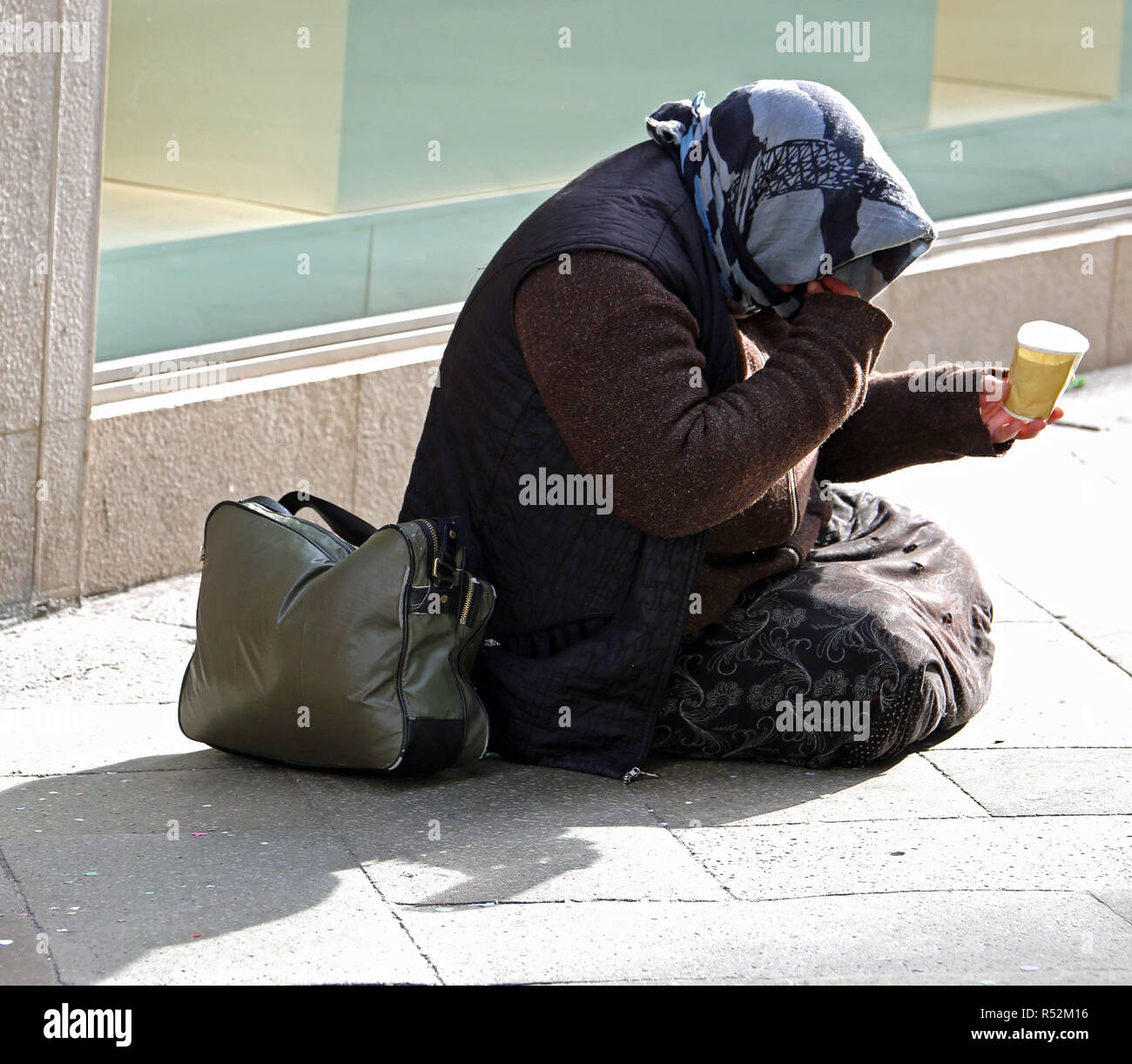 old gypsy woman begging for people while she is squatting in the middle ...