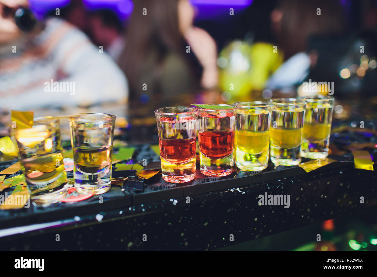 Variation of hard alcoholic shots served on bar counter. Blur bottles ...