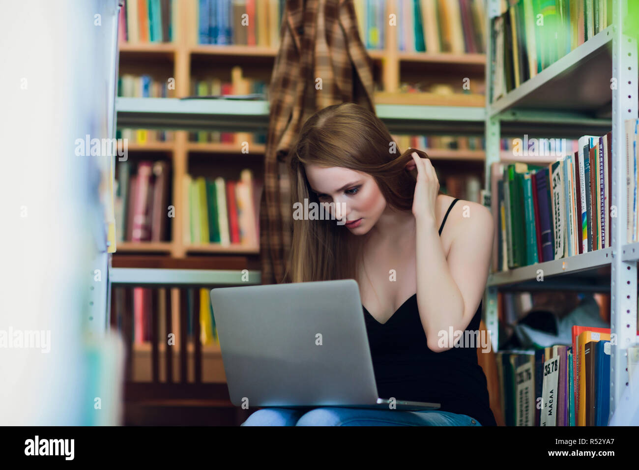 Happy smiling female student working with laptop in library Stock Photo ...