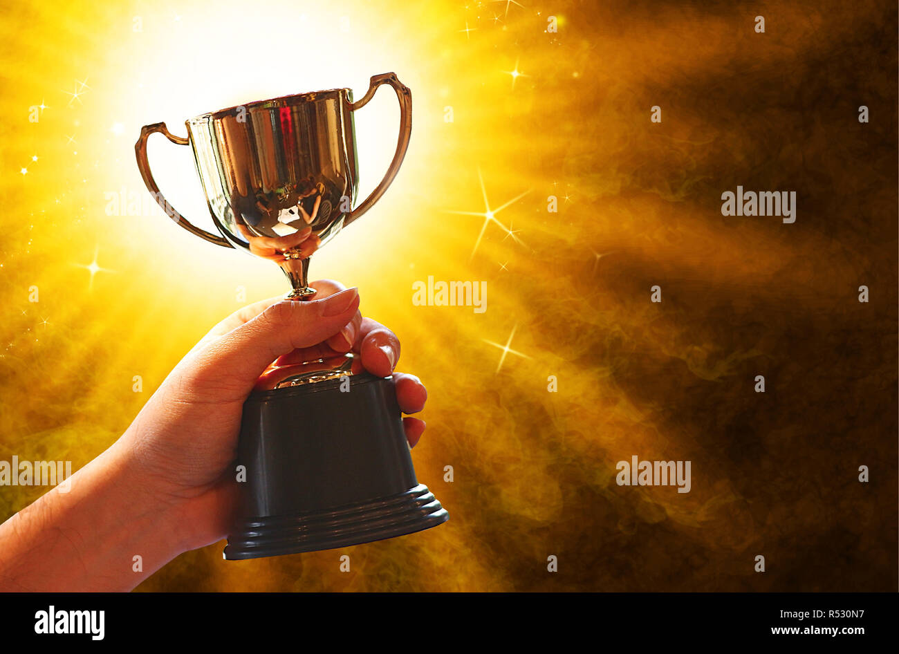 Winner hold trophy with abstract spotlight background Stock Photo - Alamy