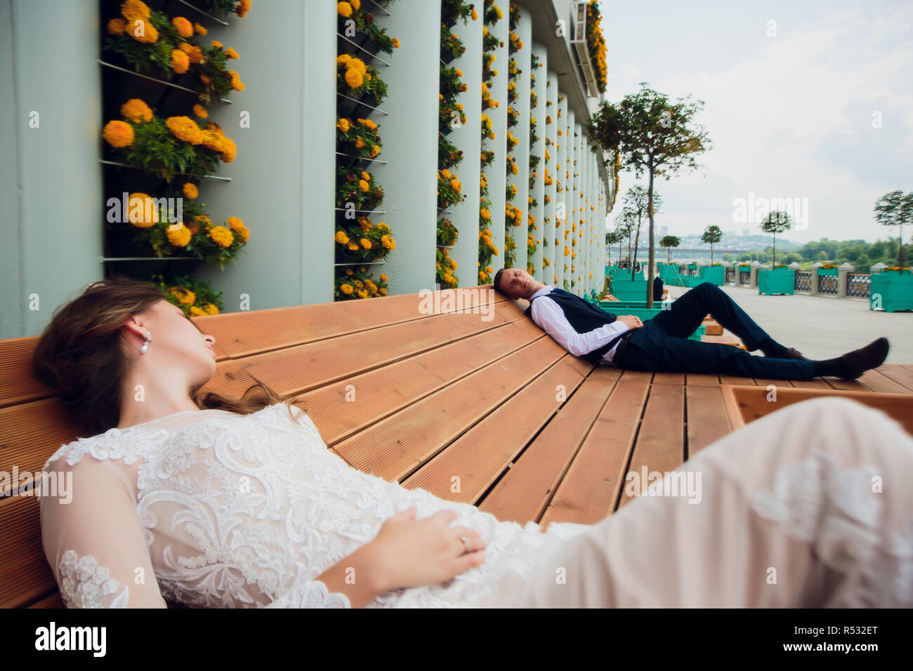 two lovers sit on a bench, newlyweds crouched to rest in each other's ...