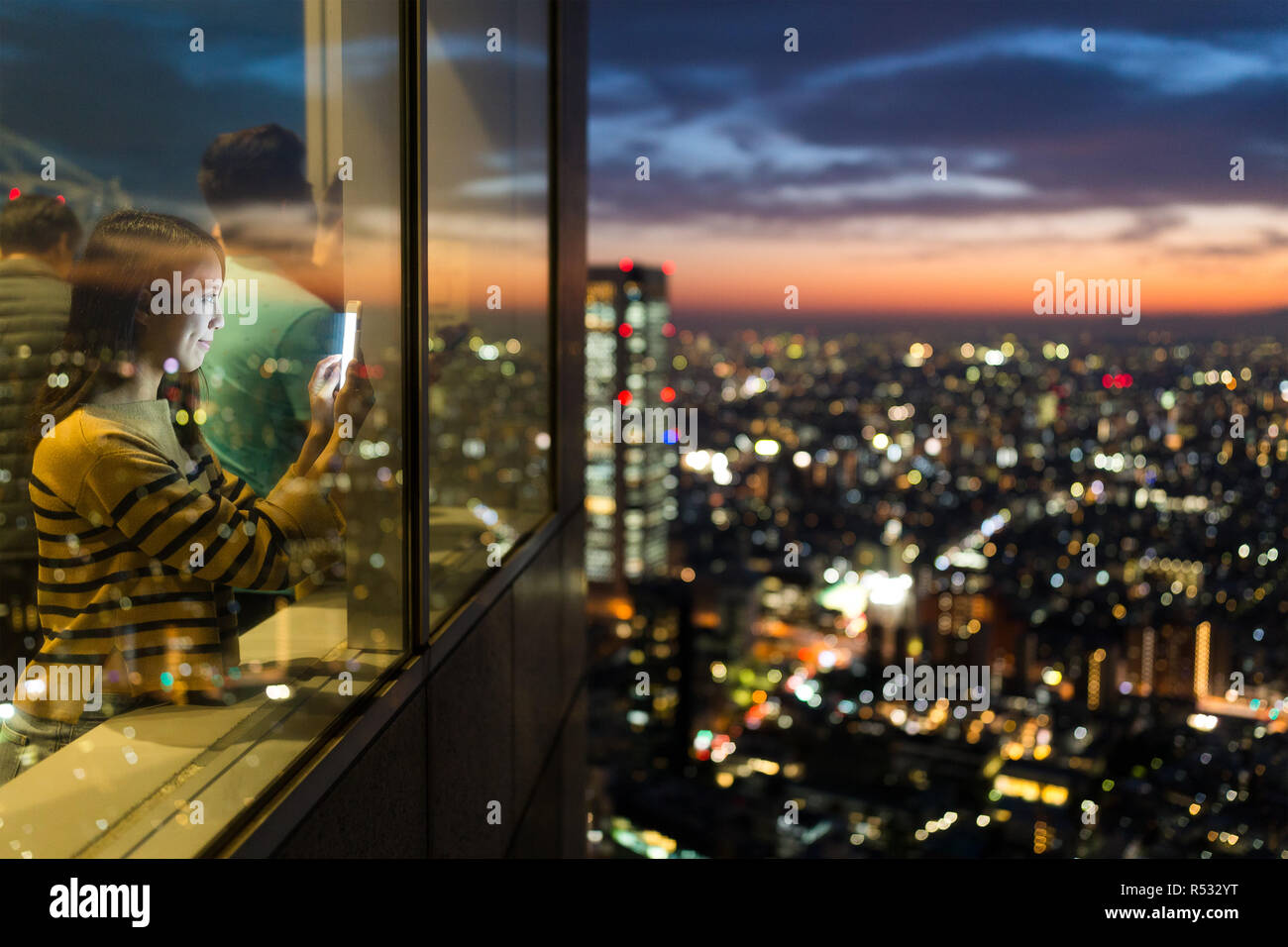 Woman visit the observatory and taking photo of the sunset in Tokyo ...
