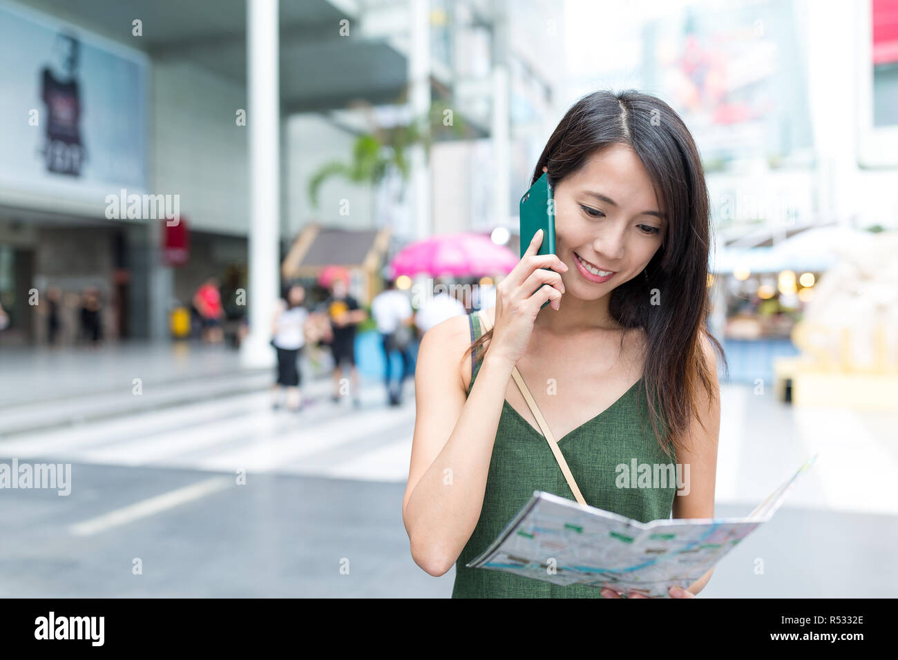 Woman asking the direction by cellphone with city map Stock Photo - Alamy