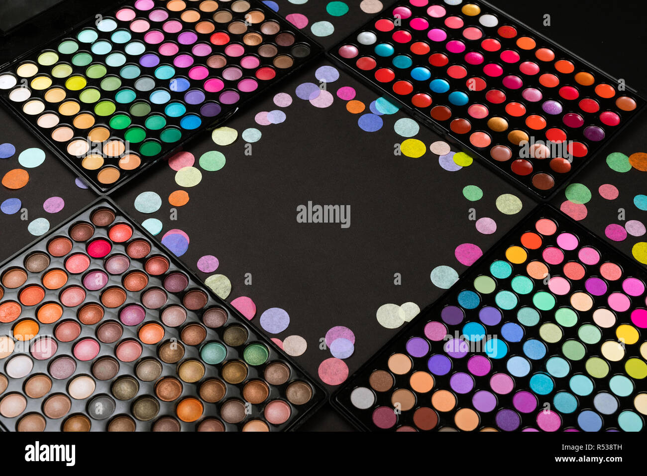 Make-up palettes with scattered colorful confetti on black background ...