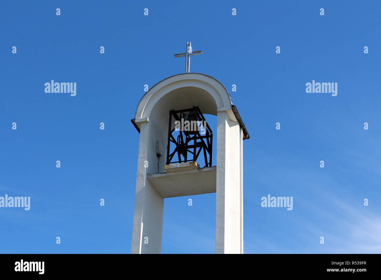 Modern white church bell tower with large open metal bell mechanism ...