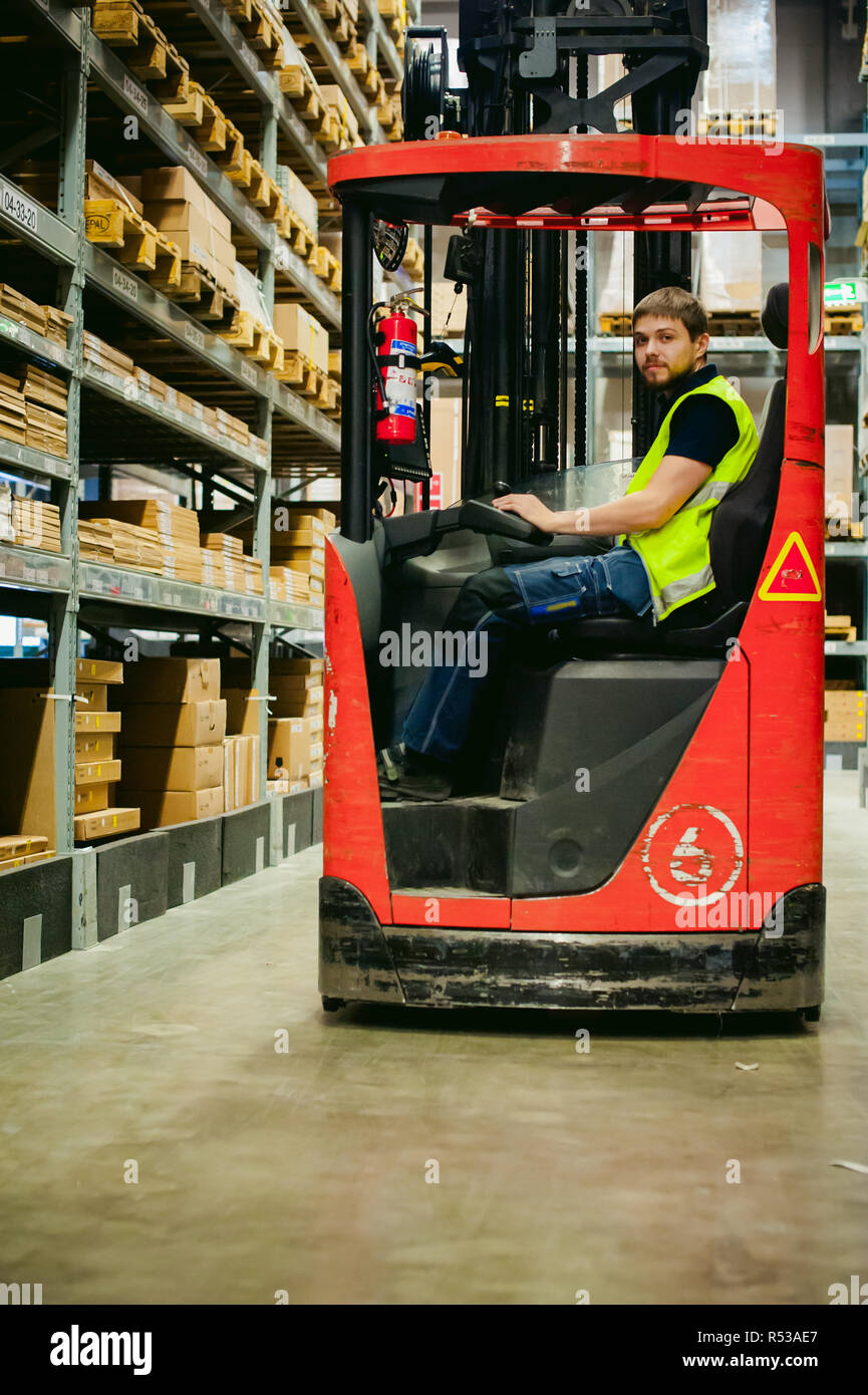 young man in working clothes, driver Reachtruck busy working on the ...