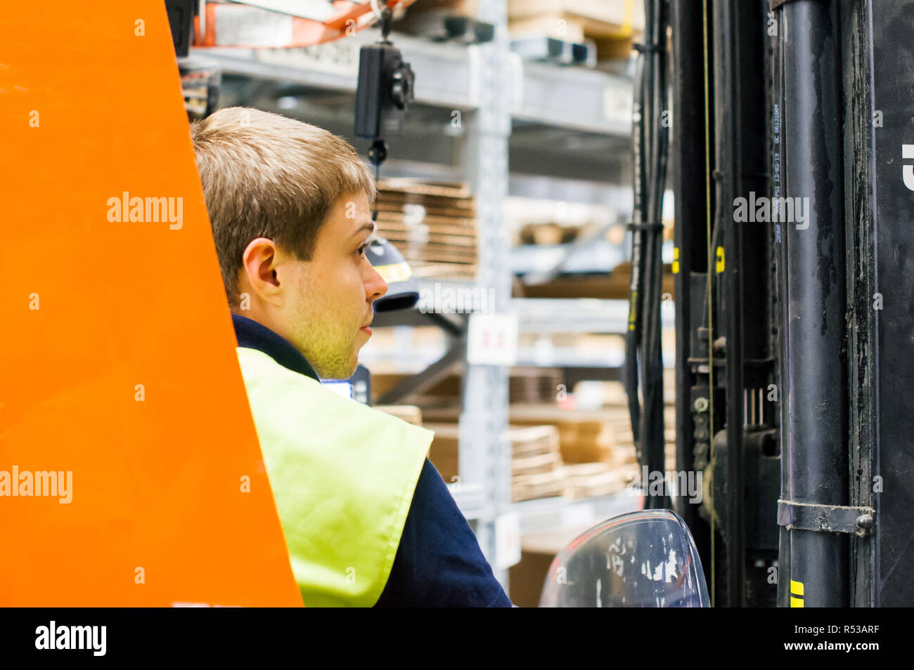 young man in working clothes, driver Reachtruck busy working on the ...