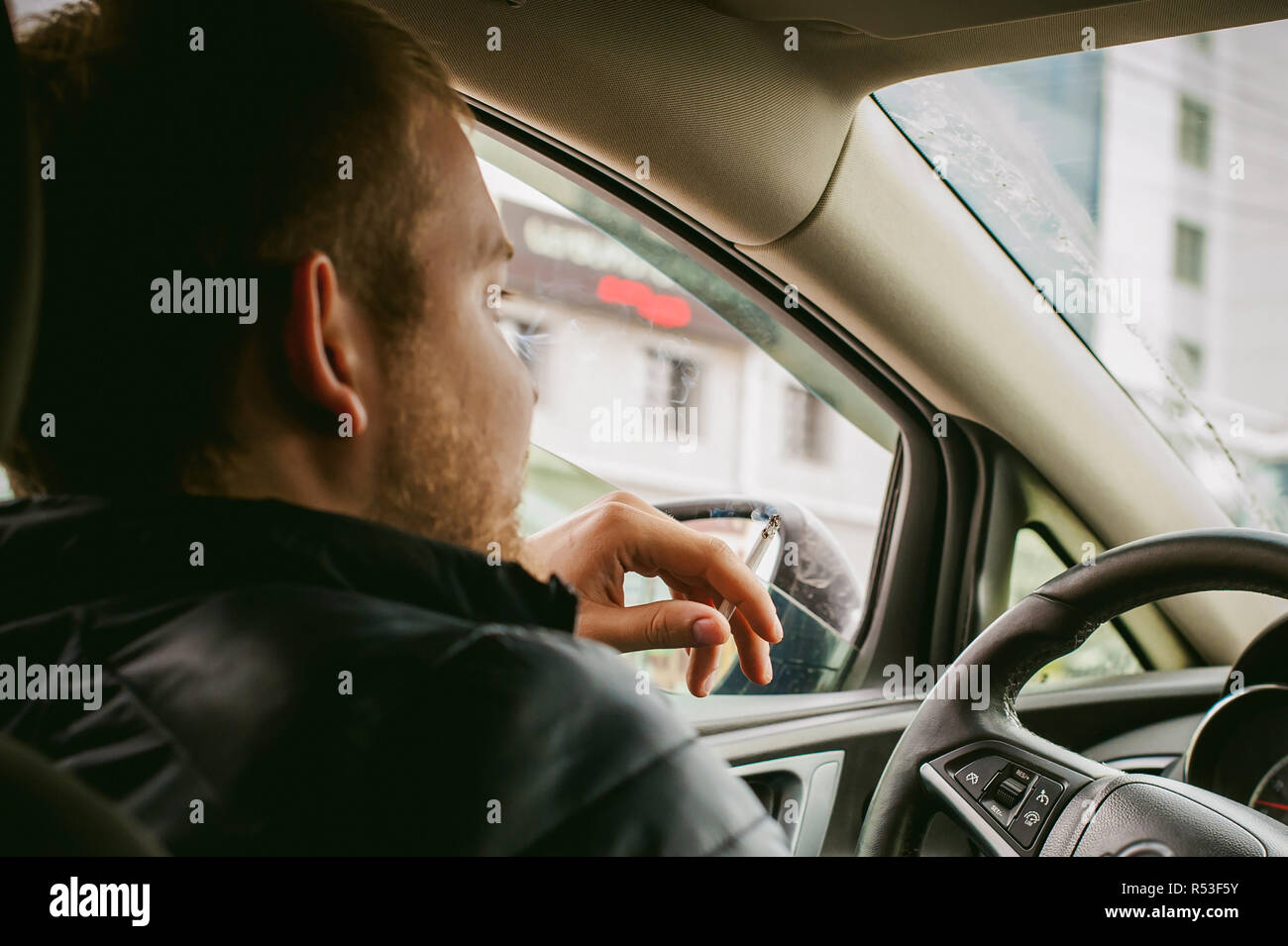 man drives a car. A guy in a jacket sits behind the wheel of a car ...