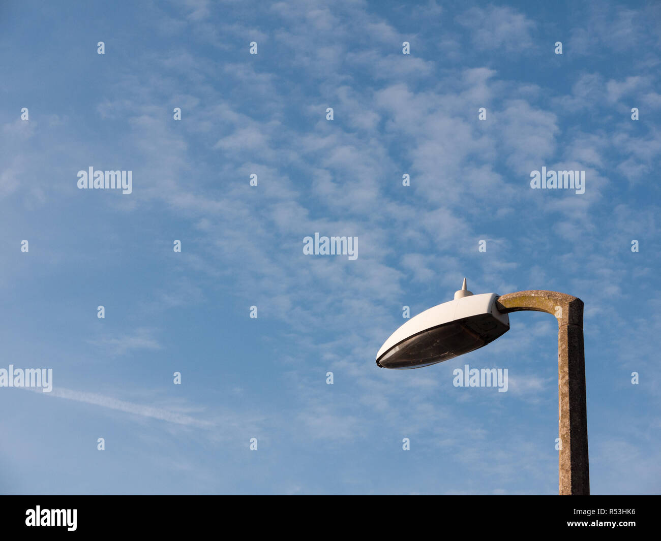 the top of a street light outside turned off during day with a blue and ...