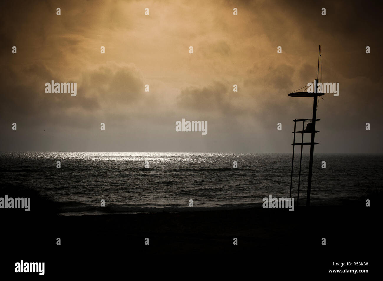 Backlight of a baywatch chair on the beach at sunrise with sunbeams ...