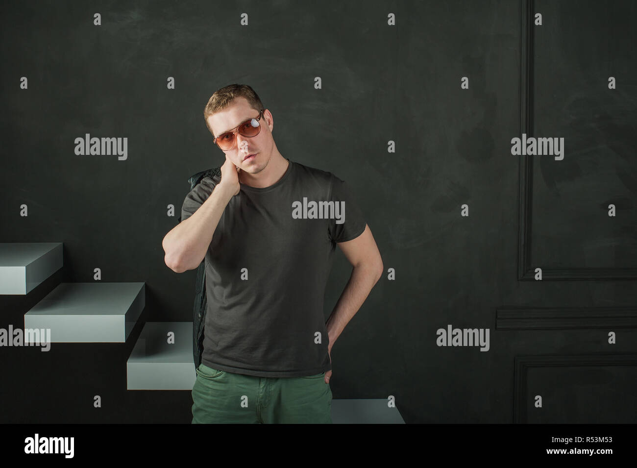 studio photography young brutal guy. man in sunglasses, T-shirt, jeans ...