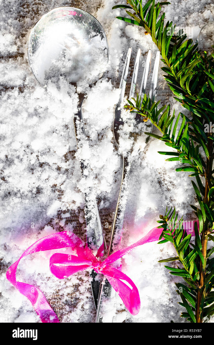 winter Cutlery with pink ribbon as border on white snowy background ...
