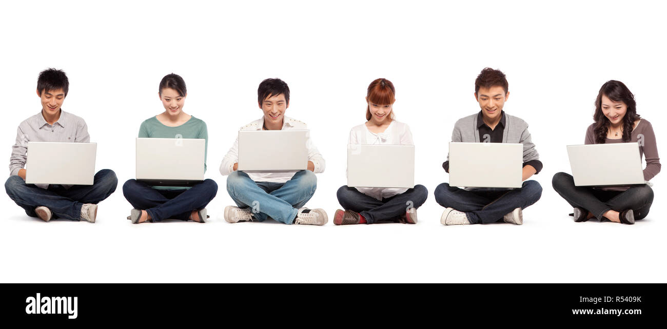 Six young people sitting in a row using their laptop computers Stock ...
