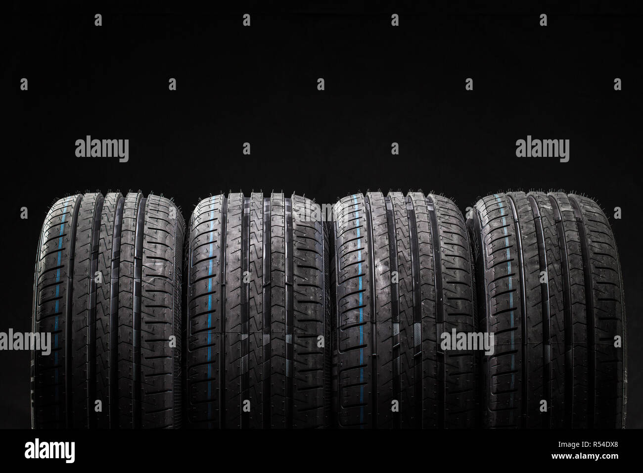 Stack of brand new high performance car tires on clean low-key black ...