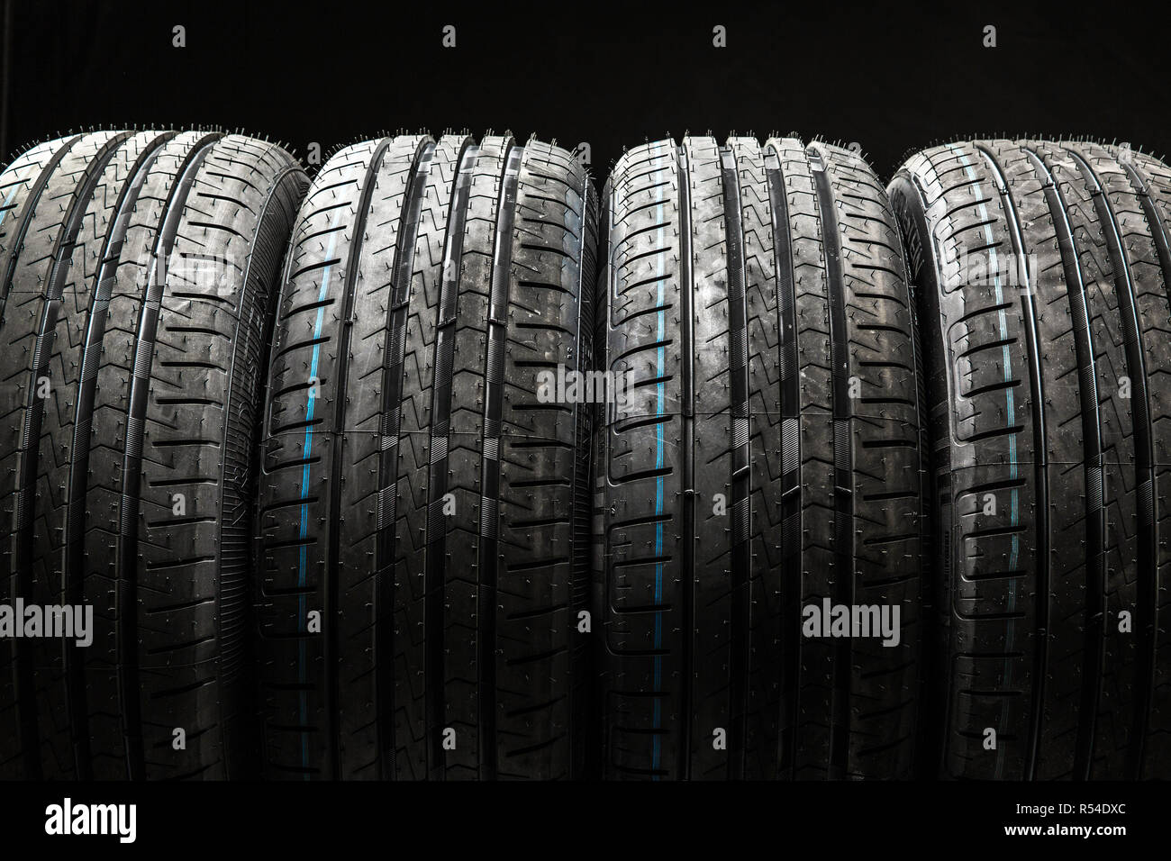 Stack of brand new high performance car tires on clean low-key black ...