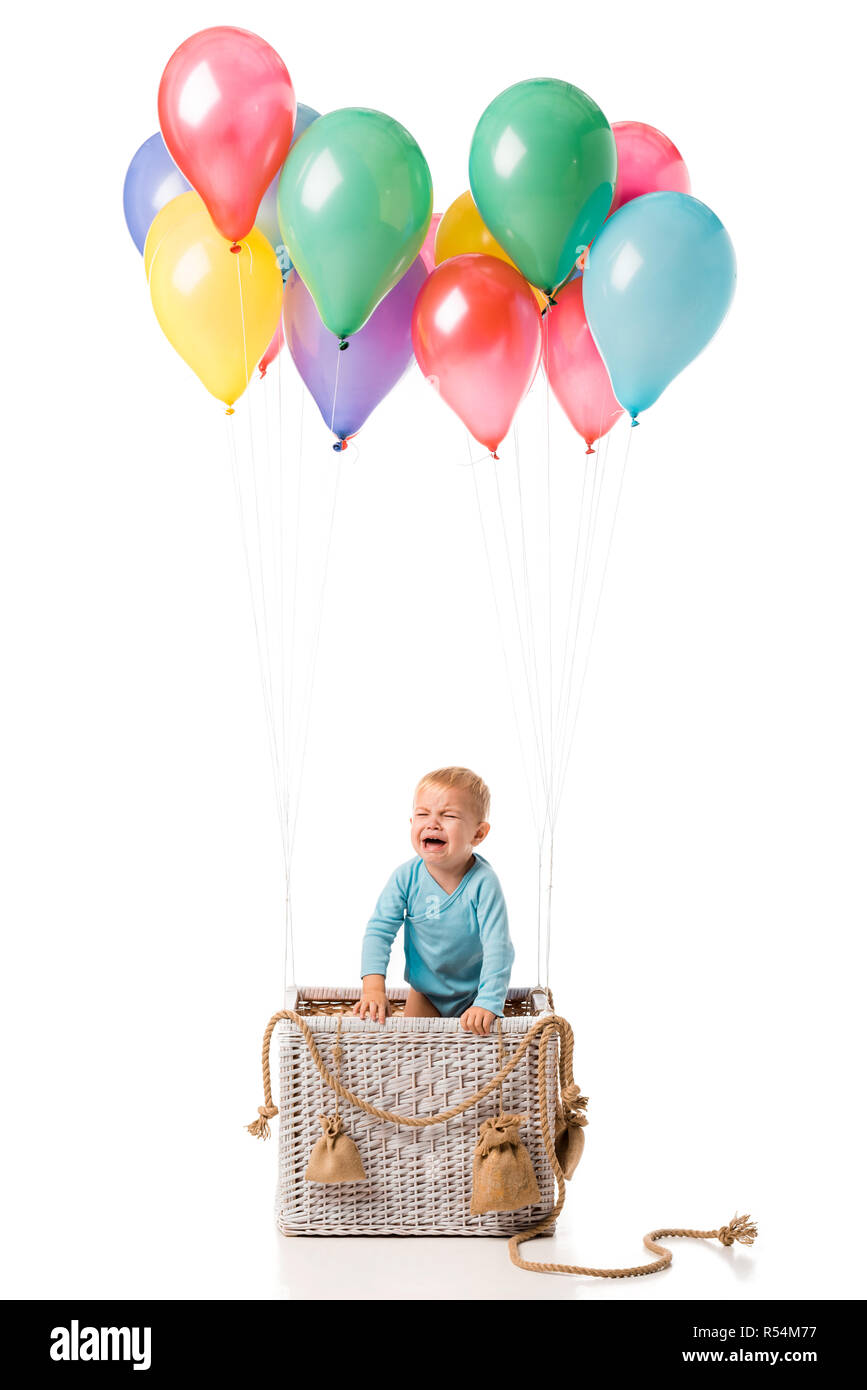 toddler boy crying and standing in wicker basket with multicolored ...
