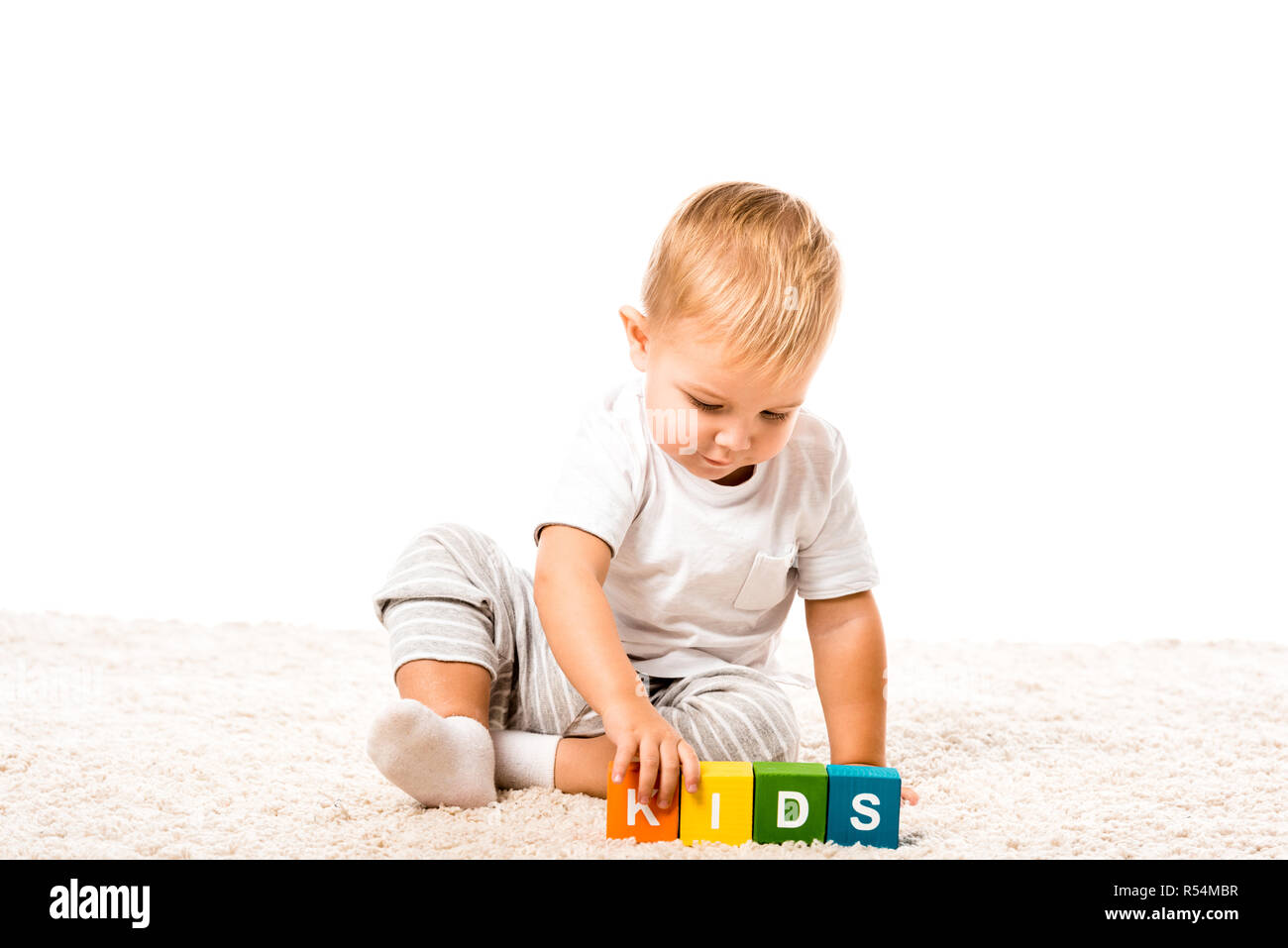 cute toddler boy playing colored cubes with letters on carpet isolated ...