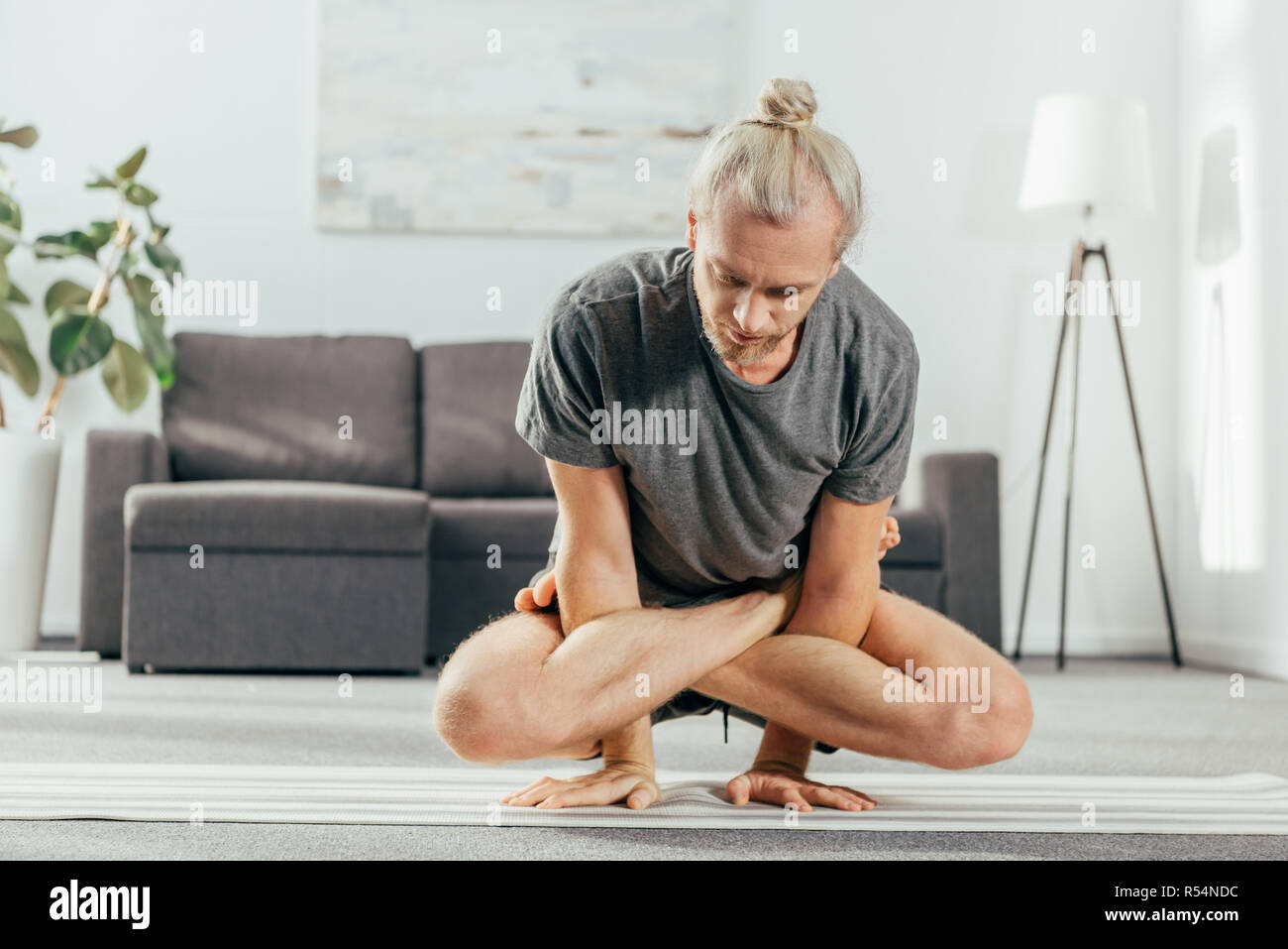 adult man practicing yoga at home and doing arm balance exercise with ...