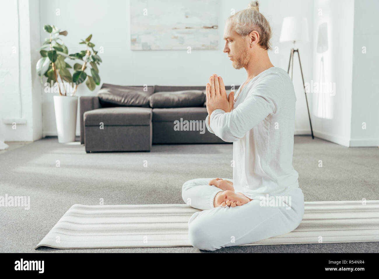 side view of man meditating in lotus position with namaste gesture at ...