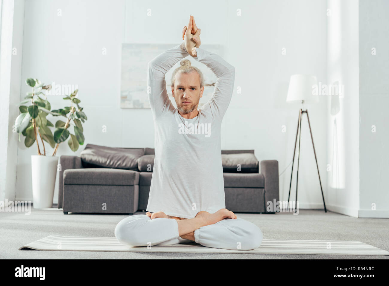 man sitting in lotus position with mudra sign and looking at camera ...