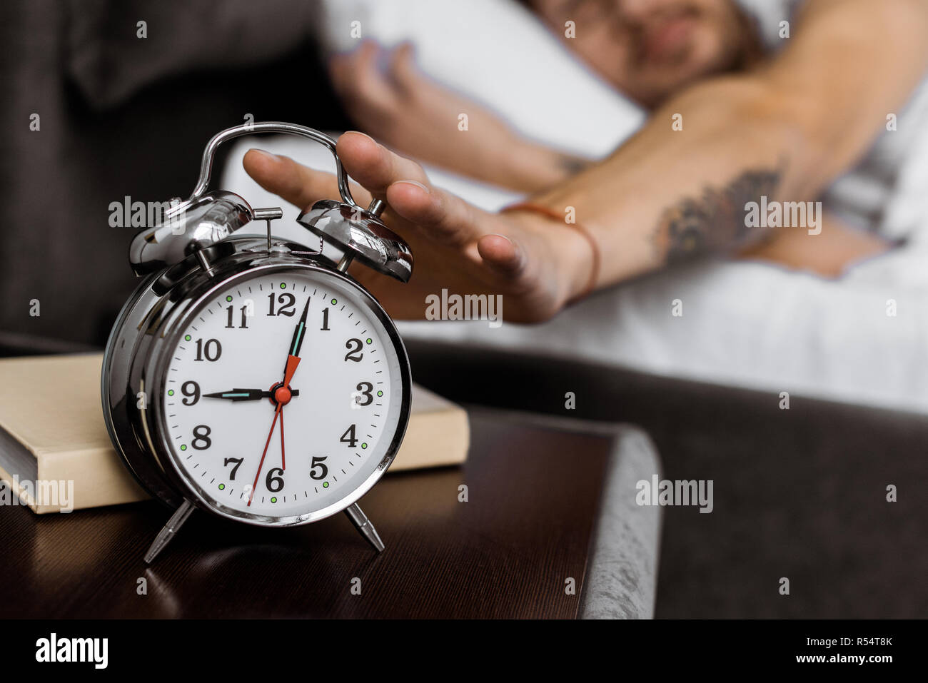 close-up view of young man turning off alarm clock while waking up in ...