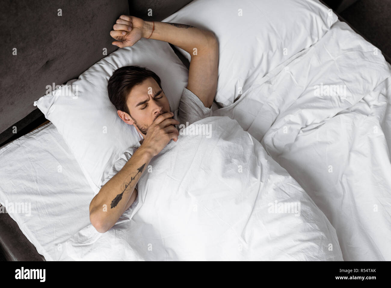 top view of young man stretching and yawning while waking up in bed Stock Photo - Alamy