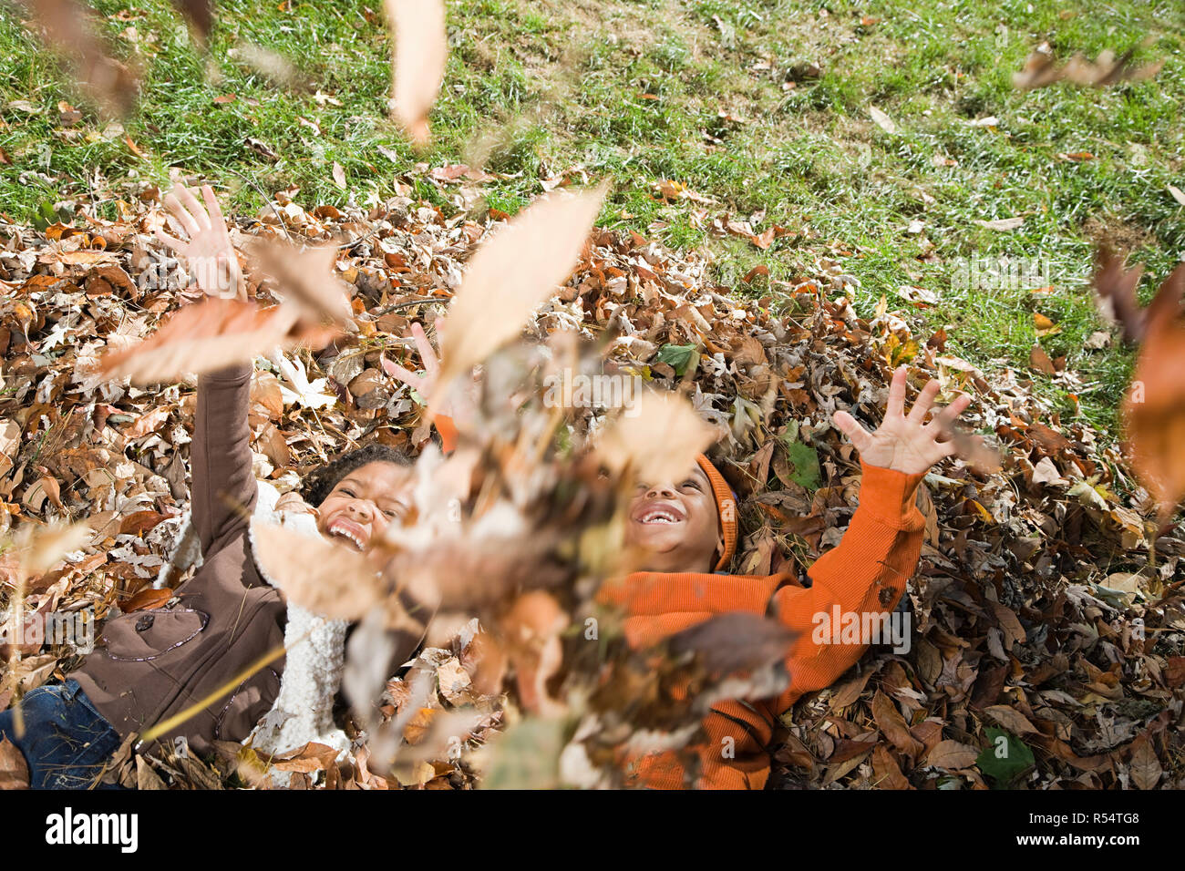 Kids playing in leaves Stock Photo - Alamy