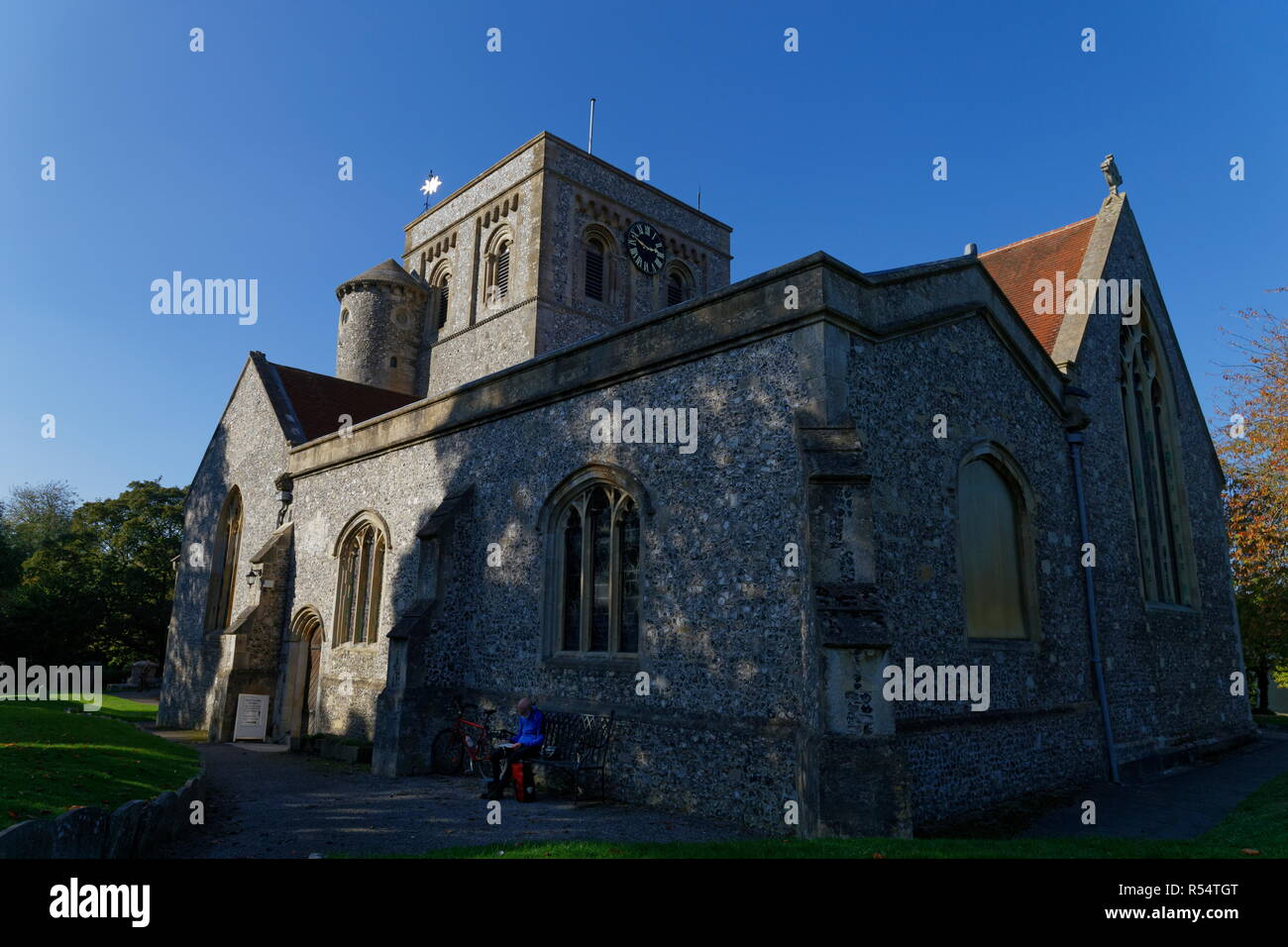 St Mary's church with a cyclist sitting on a bench Kingsclere Hampshire ...