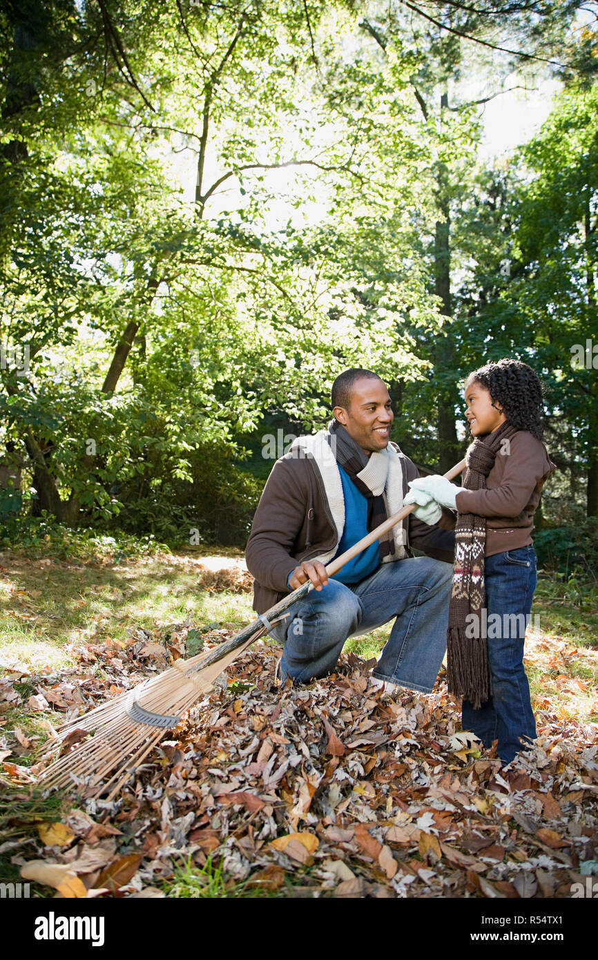 Father and daughter raking leaves Stock Photo - Alamy