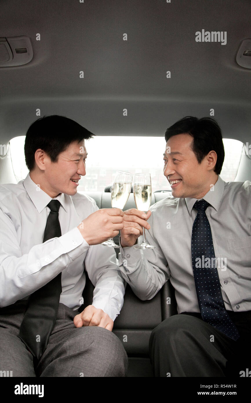 Businessmen toasting in back of car Stock Photo - Alamy