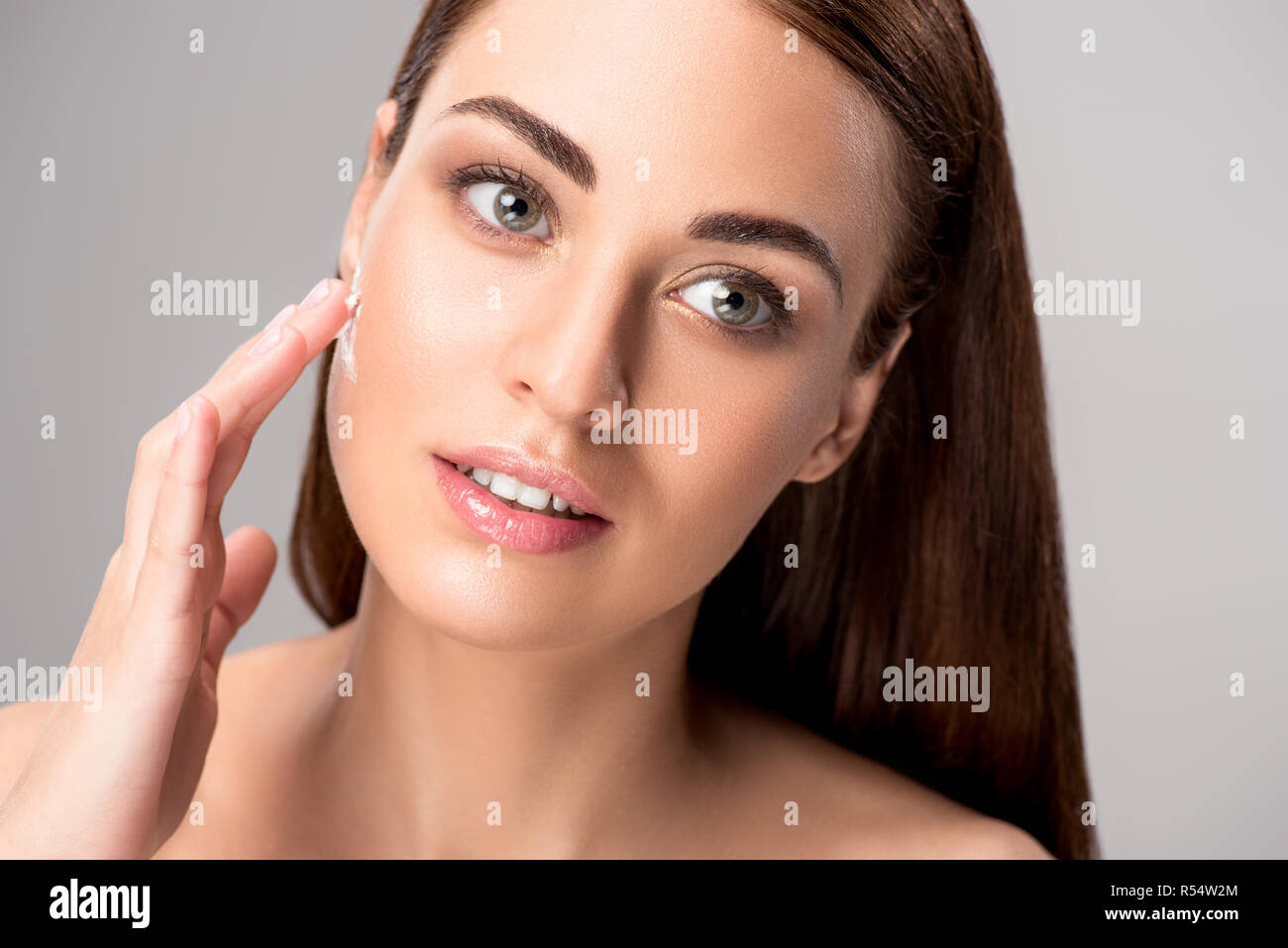 beautiful woman applying anti-wrinkle cream on face, isolated on grey ... beautiful woman applying anti-wrinkle cream on face, isolated on grey ...